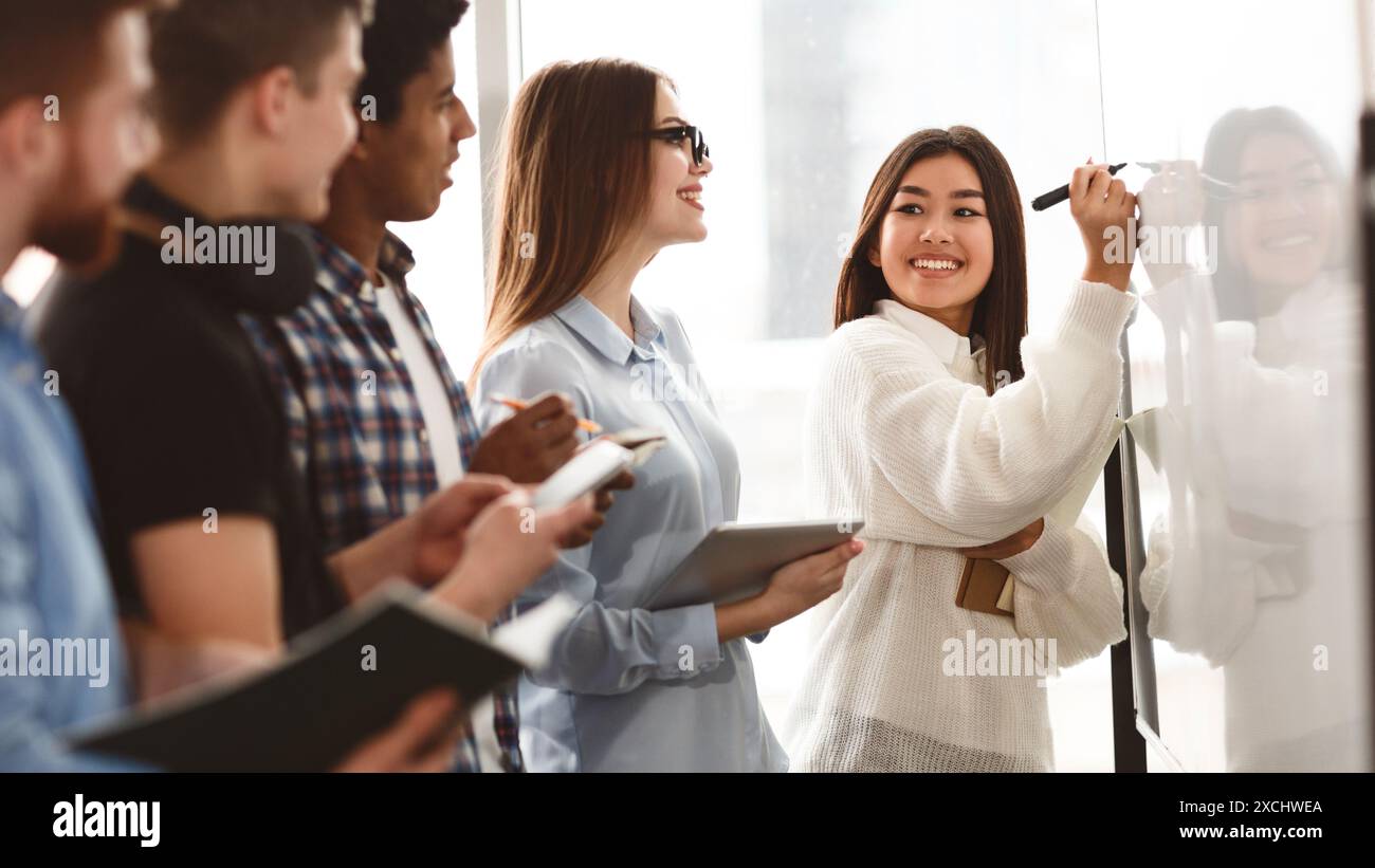 Girl showing answers on whiteboard in classroom Stock Photo - Alamy