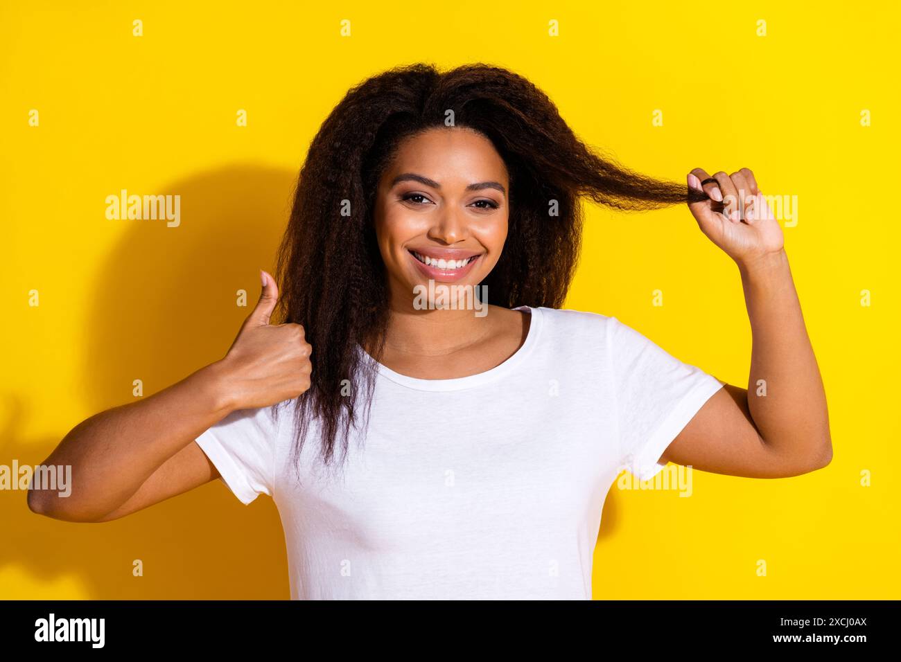 Portrait of nice young woman hold hair thumb up wear t-shirt isolated ...
