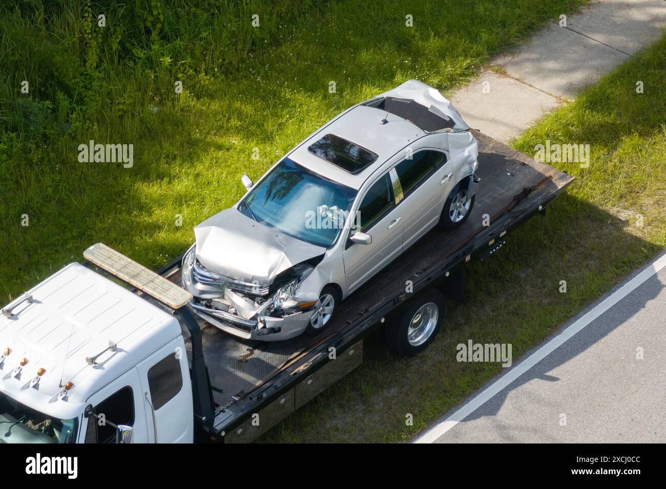 Traffic accident with tow truck hauling smashed vehicle on car crash ...