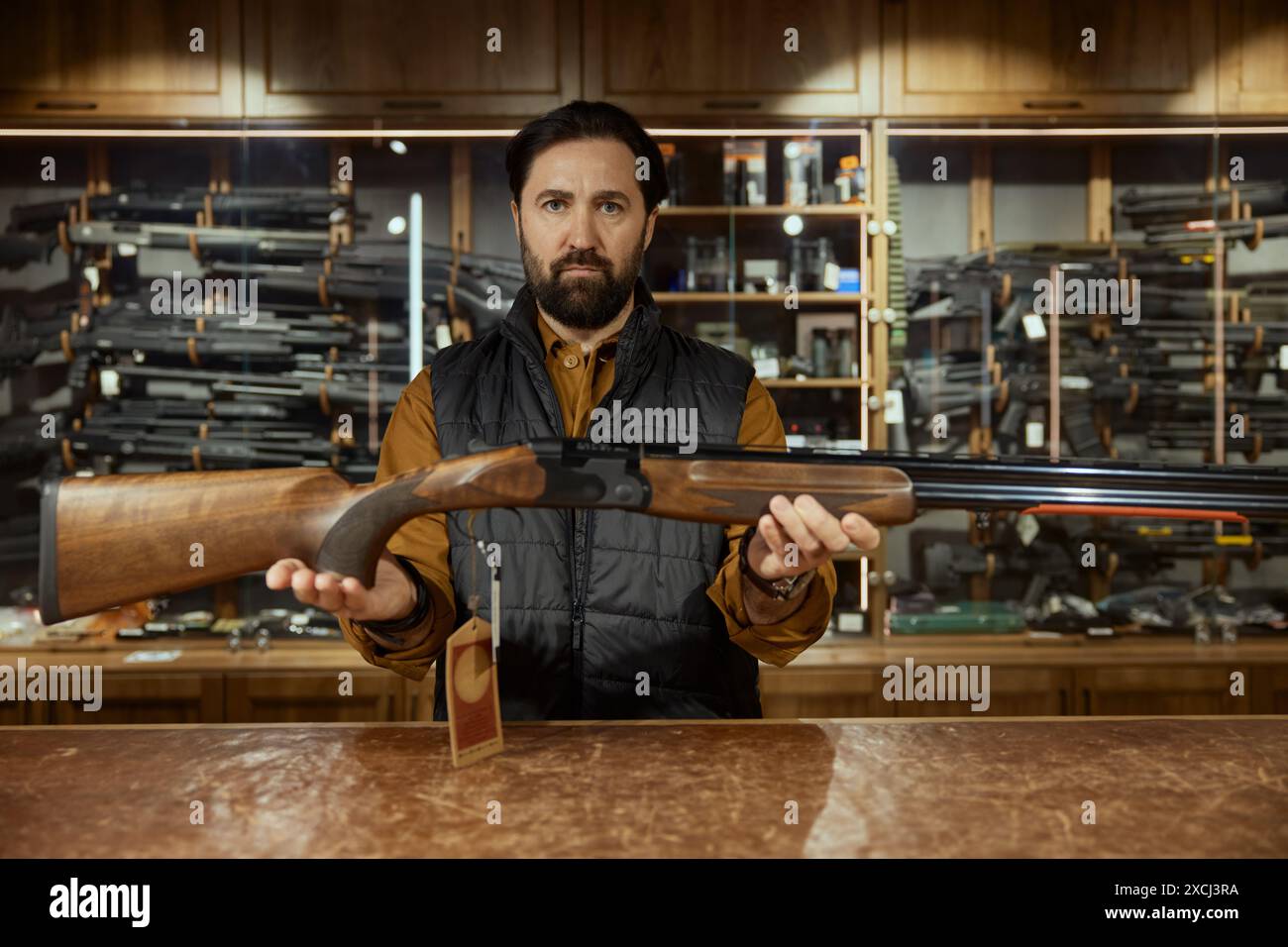 Mature man seller demonstrating gun standing at counter desk in weapon ...