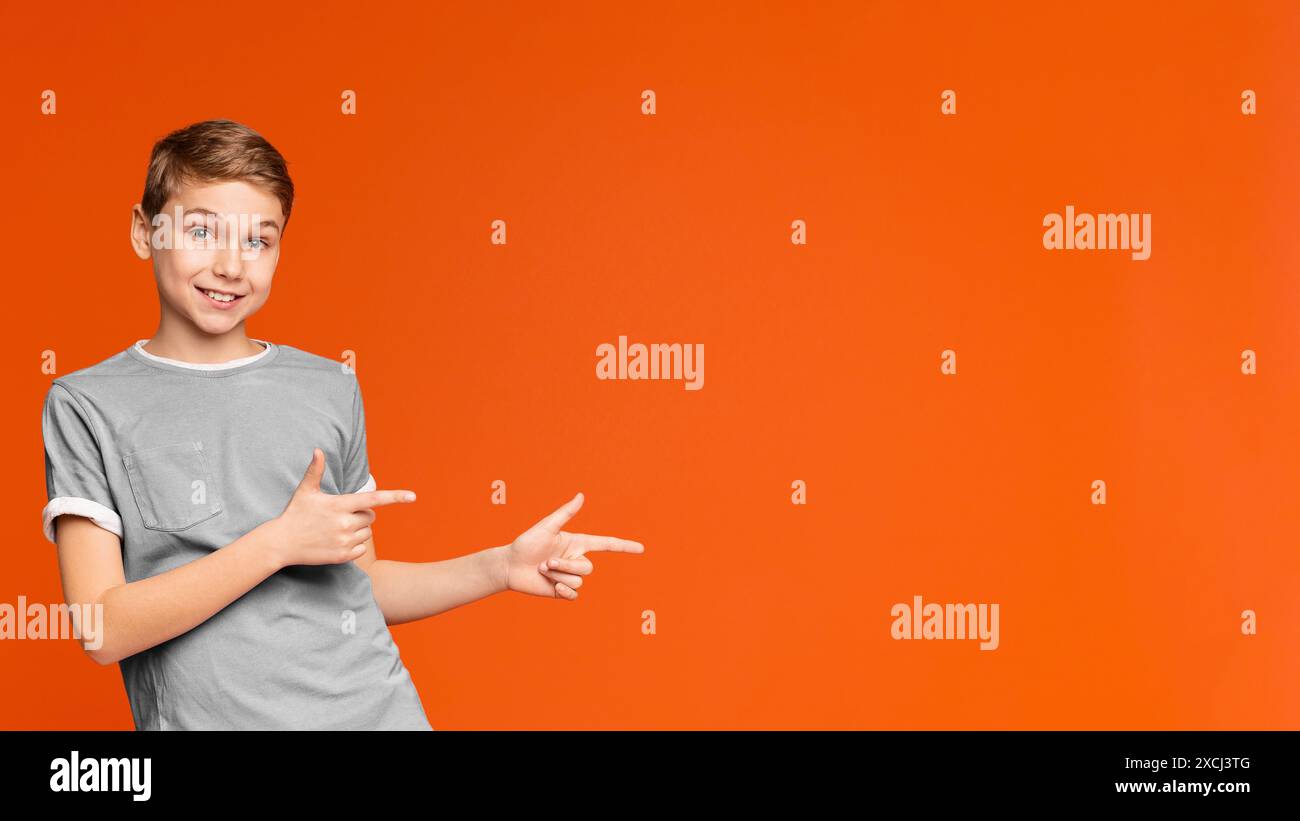 Cute little boy pointing away on orange background Stock Photo - Alamy