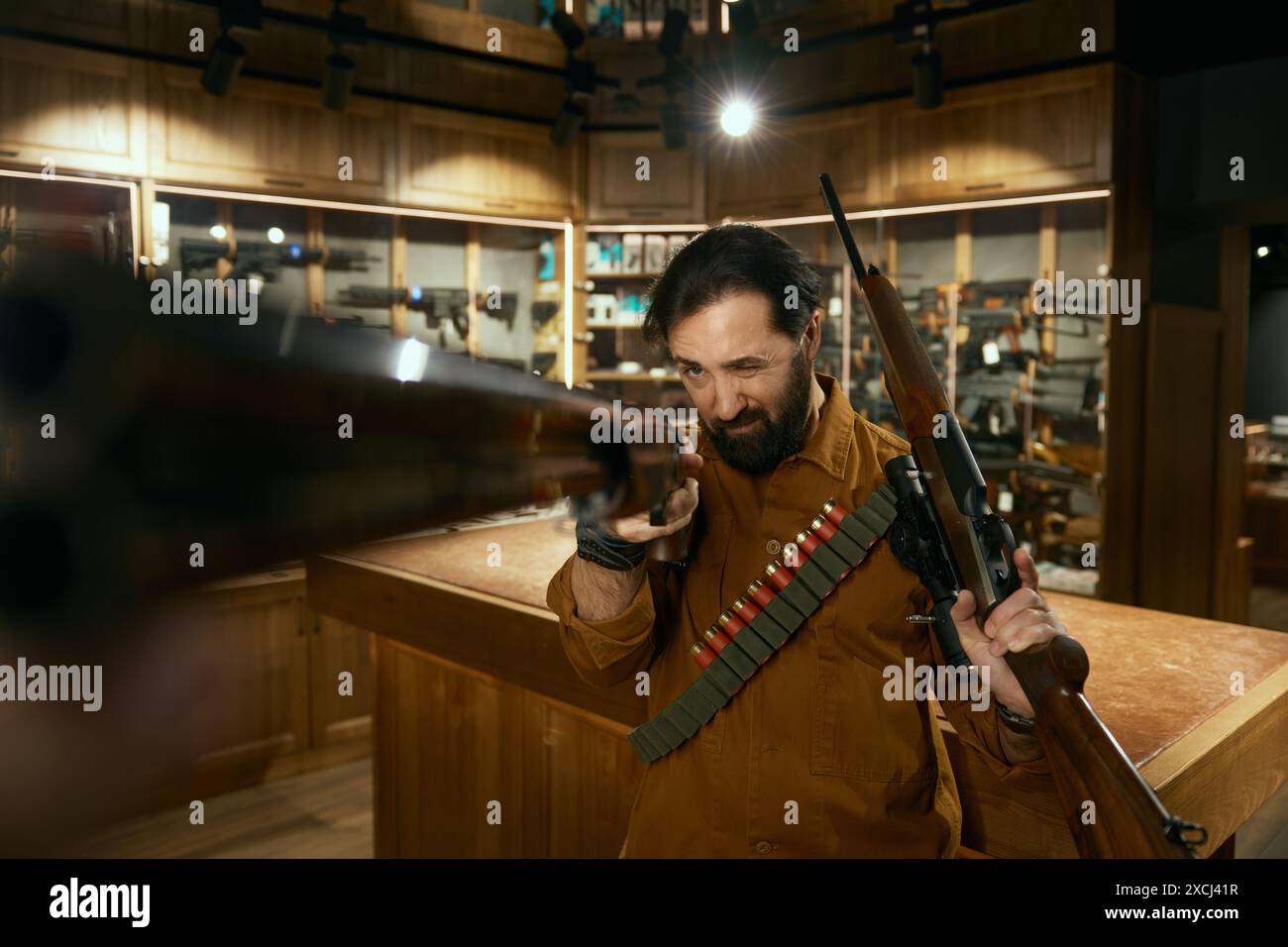 Portrait of hunter at weapon shop standing with rifles Stock Photo - Alamy