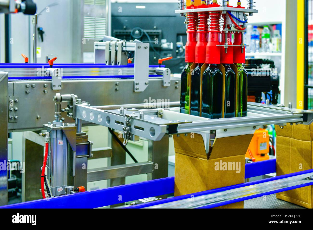 A robot arm is loading glass bottles into boxes on an automated ...