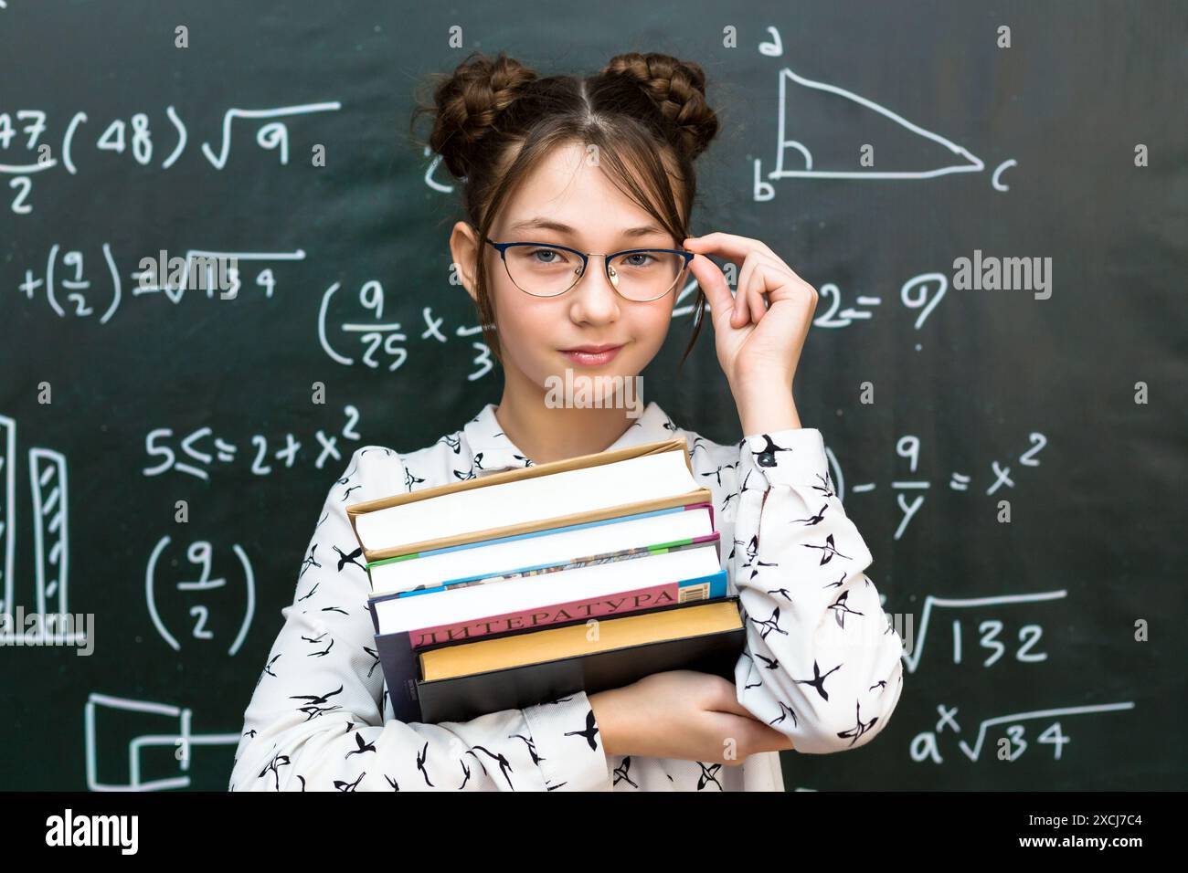 Schoolgirl girl in vision glasses in a white blouse with books in her ...