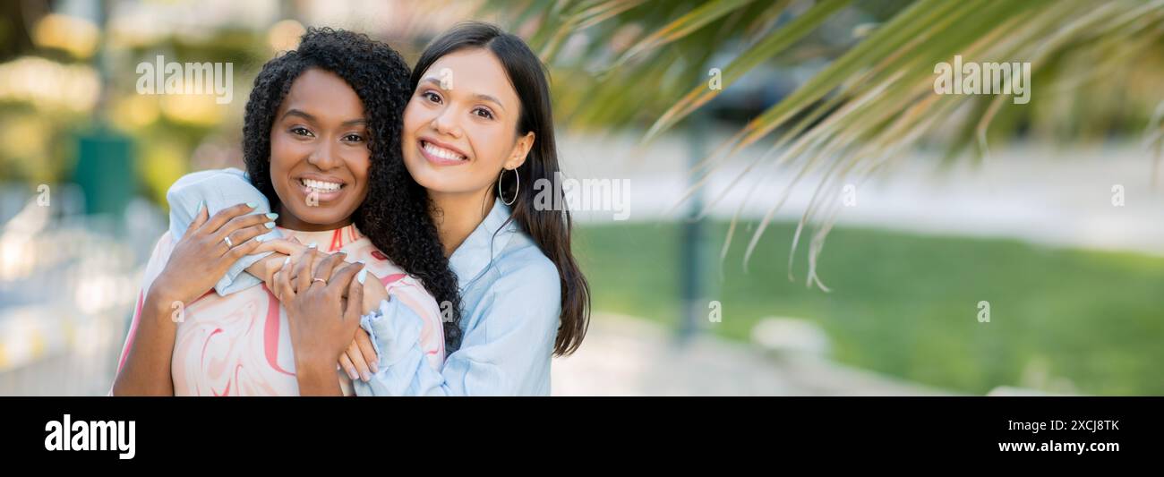 Portrait of two multiracial girlfriends hugging and posing together ...