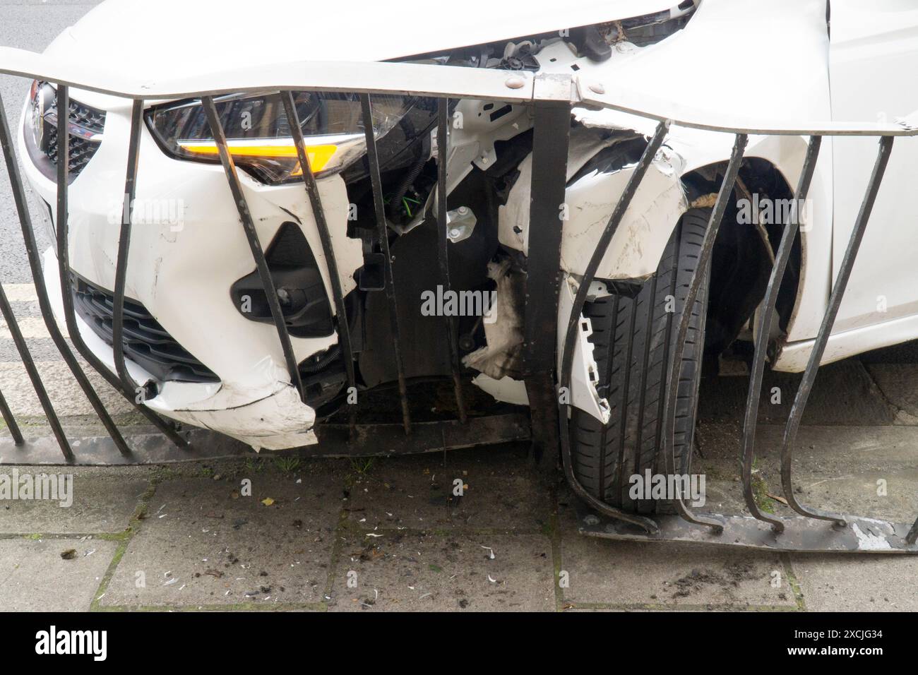 The front left wing of a white car that has crashed into railings ...