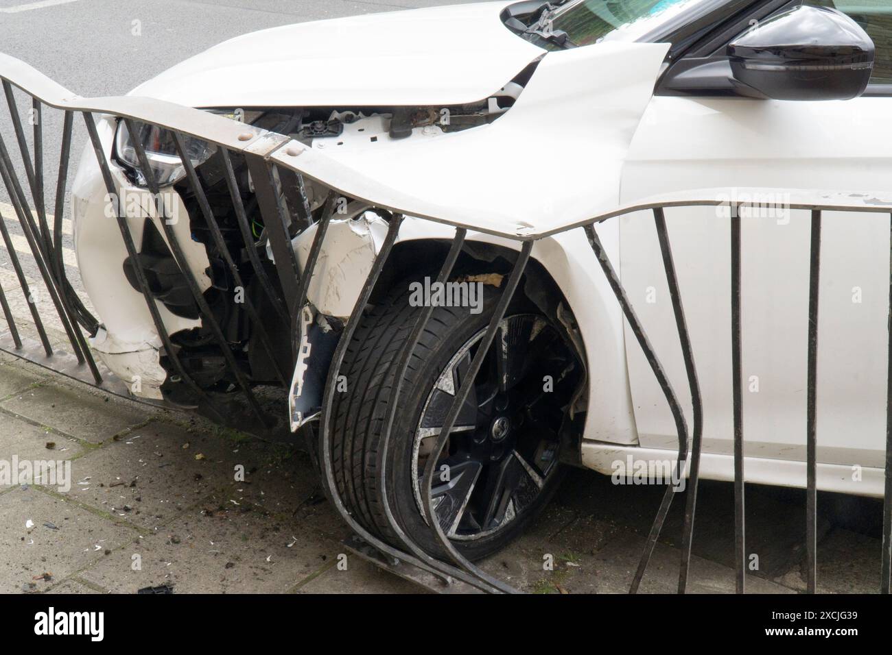 The front left wing of a white car that has crashed into railings ...