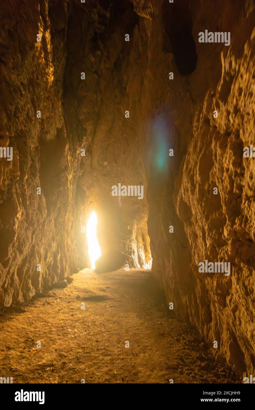 A cave with a small opening in the wall. The light shining through the ...