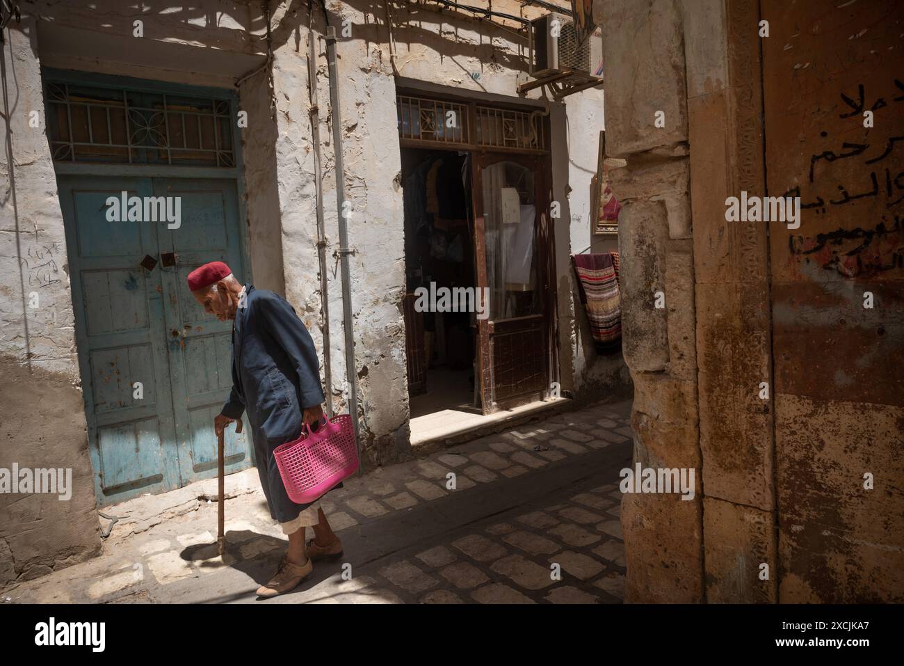 An old Tunisian man wearing a traditional red Chechia walks in the ...