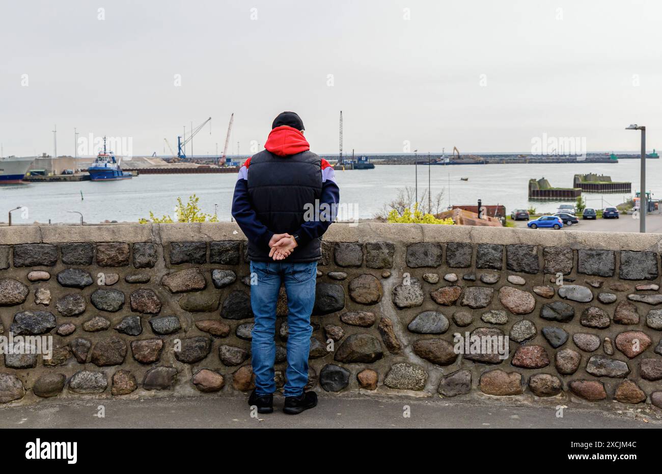 A man stands and looks at the ships in a port city by the sea. Bornholm ...
