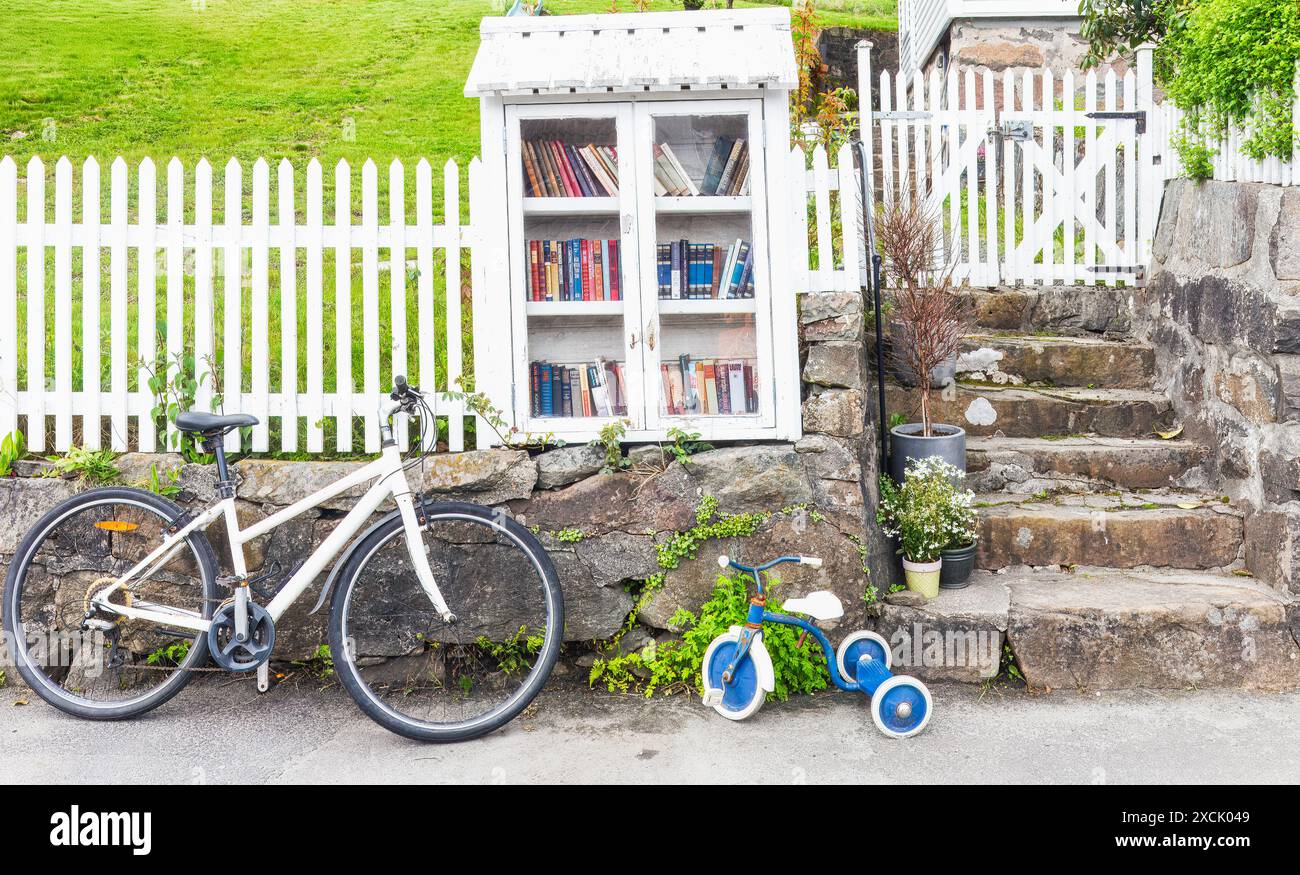 Street library with collection of books in a white wooden cabinet. A ...