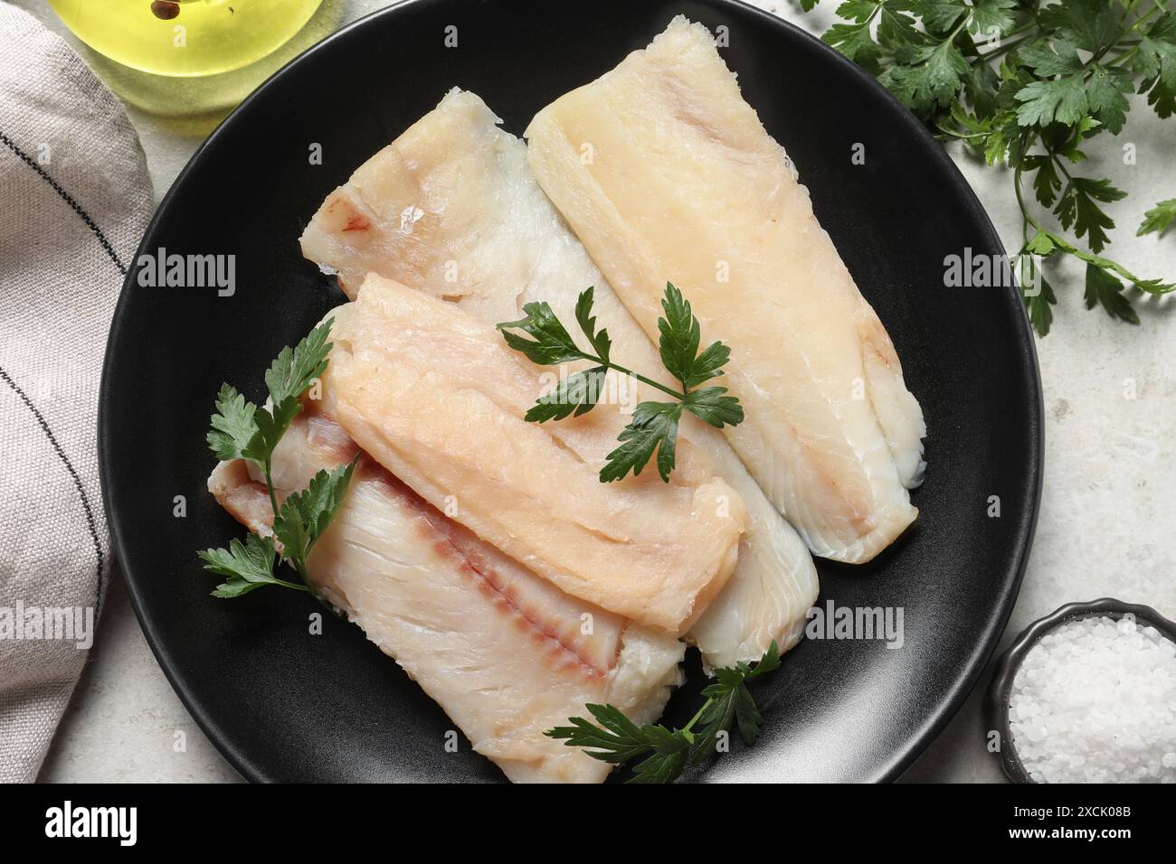 Plate with raw cod fish, parsley and salt on light table, flat lay ...