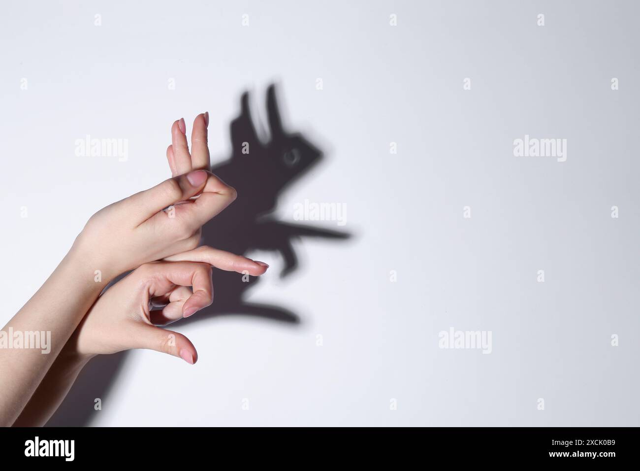 Shadow puppet. Woman making hand gesture like rabbit on light ...
