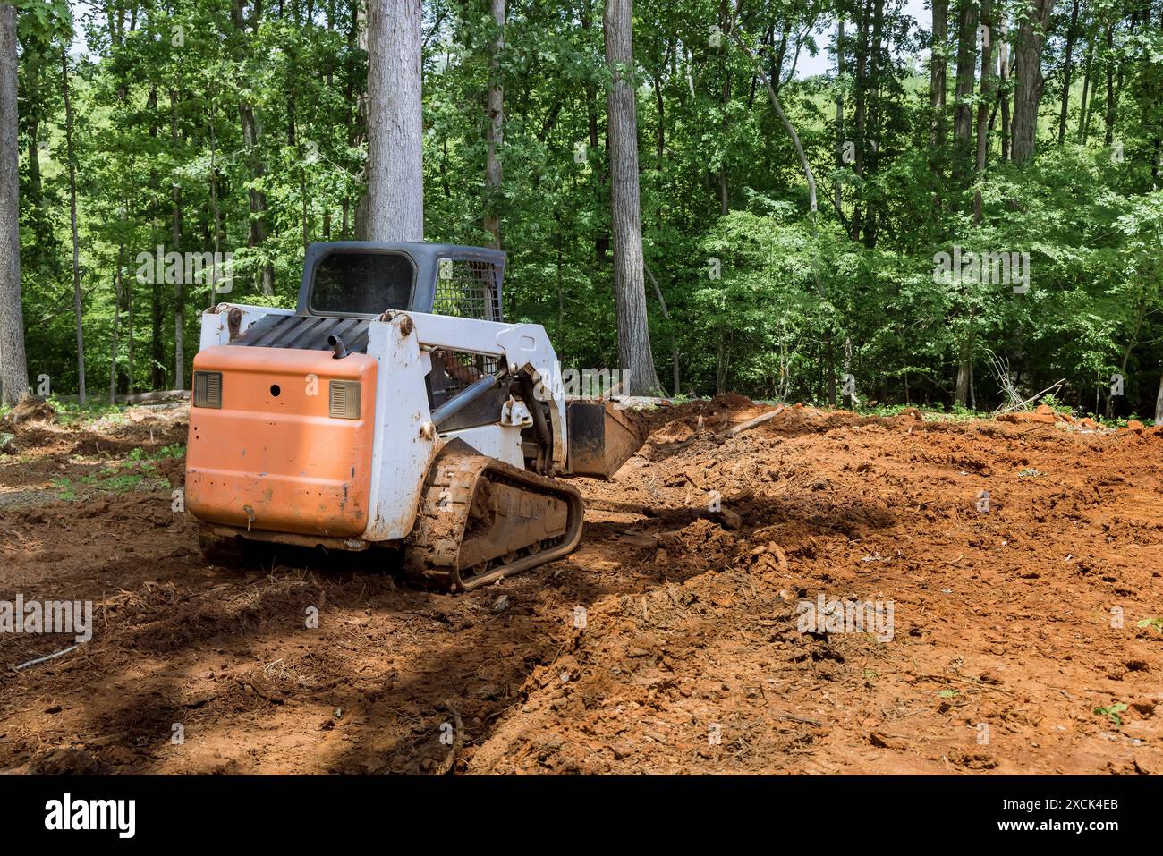 An earthmoving tractor is leveling ground during construction project ...