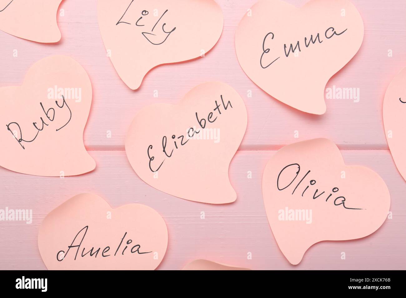 Paper stickers with different names on pink wooden background, flat lay ...