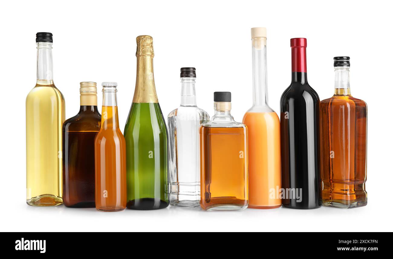 Bottles of different alcoholic drinks on white table against light ...