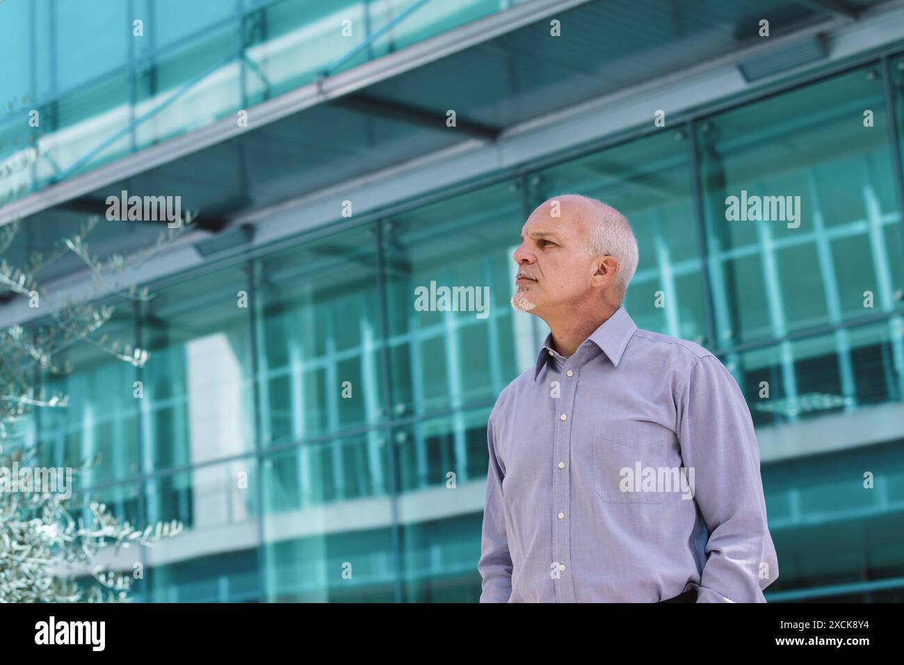 Businessman thinking outside a modern office, reflecting on technology ...