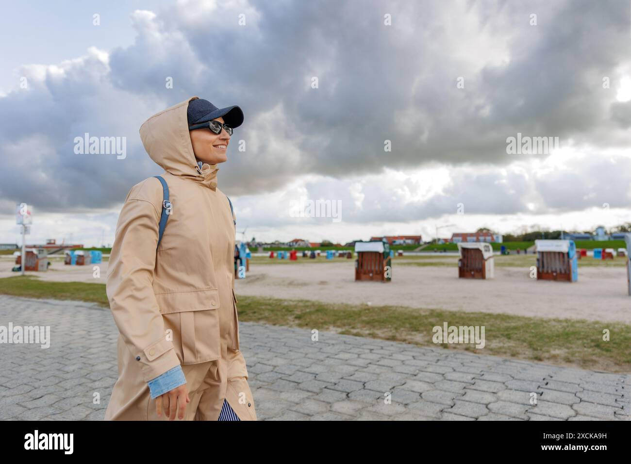Smiling happy woman running by Nord sea coast wear beige coat ...