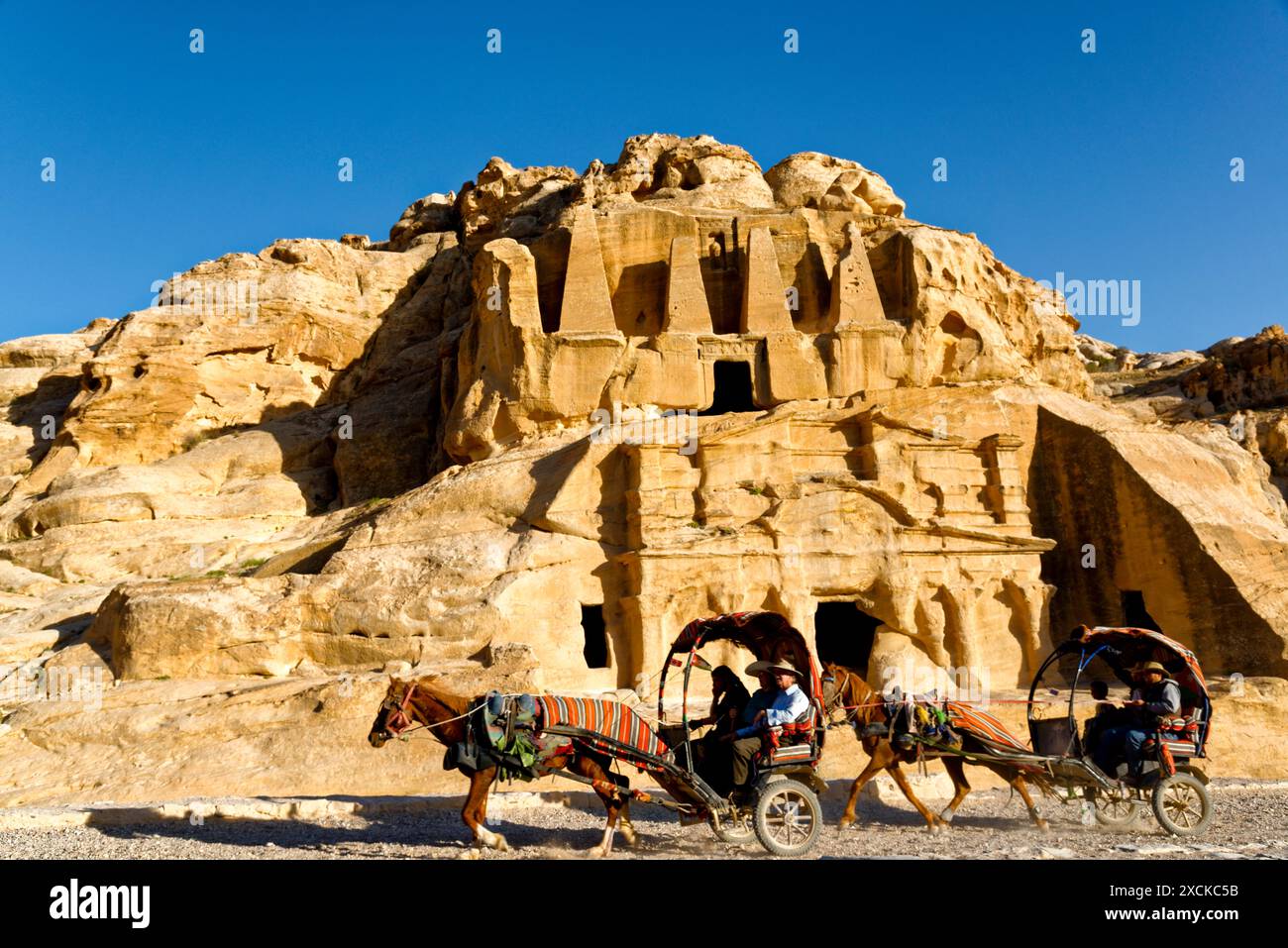 Horse carriages passing ancient rock dwelling, Petra, Jordan Stock ...