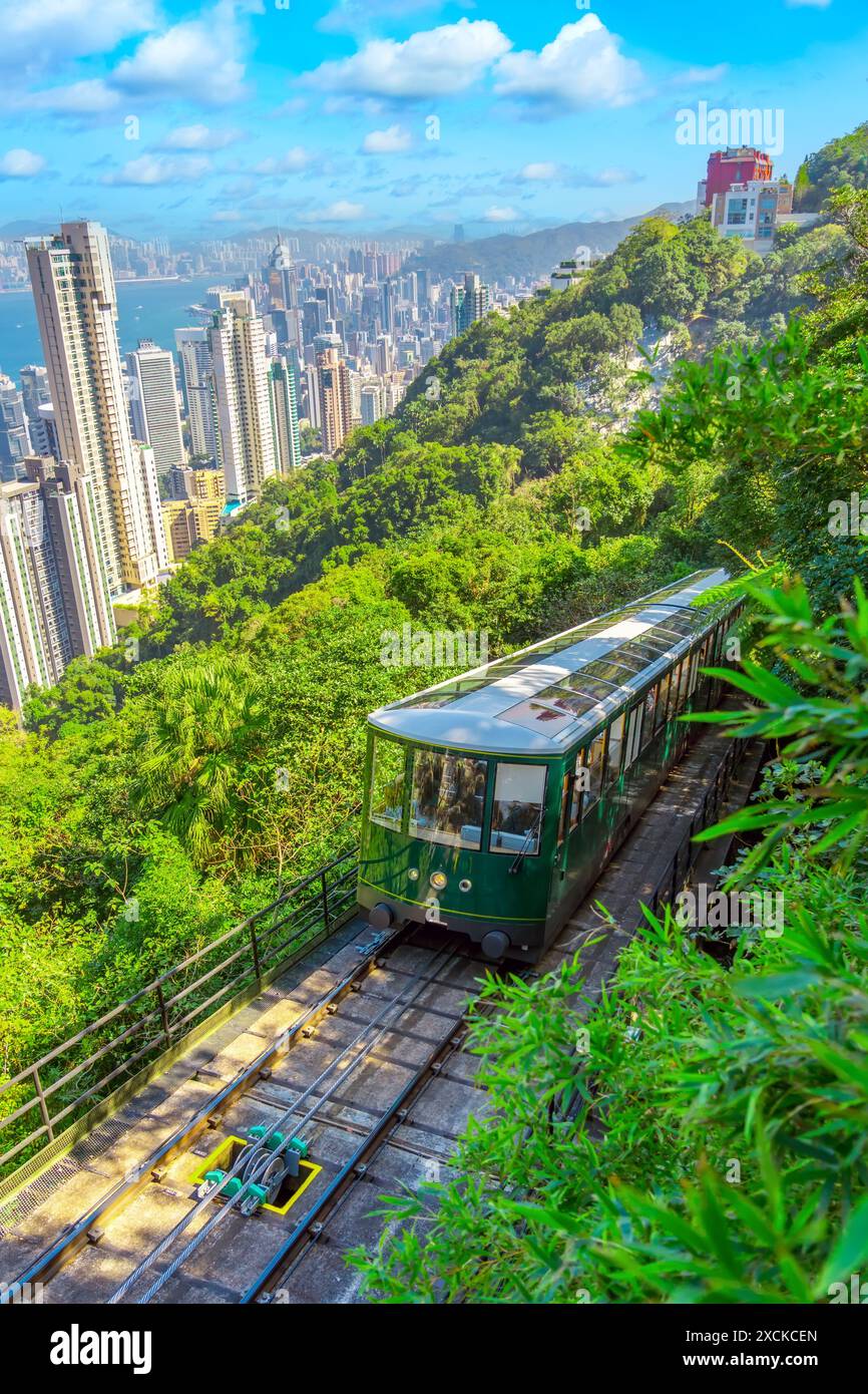The famous green tram on the slope of Victoria Peak in Hong Kong passes ...