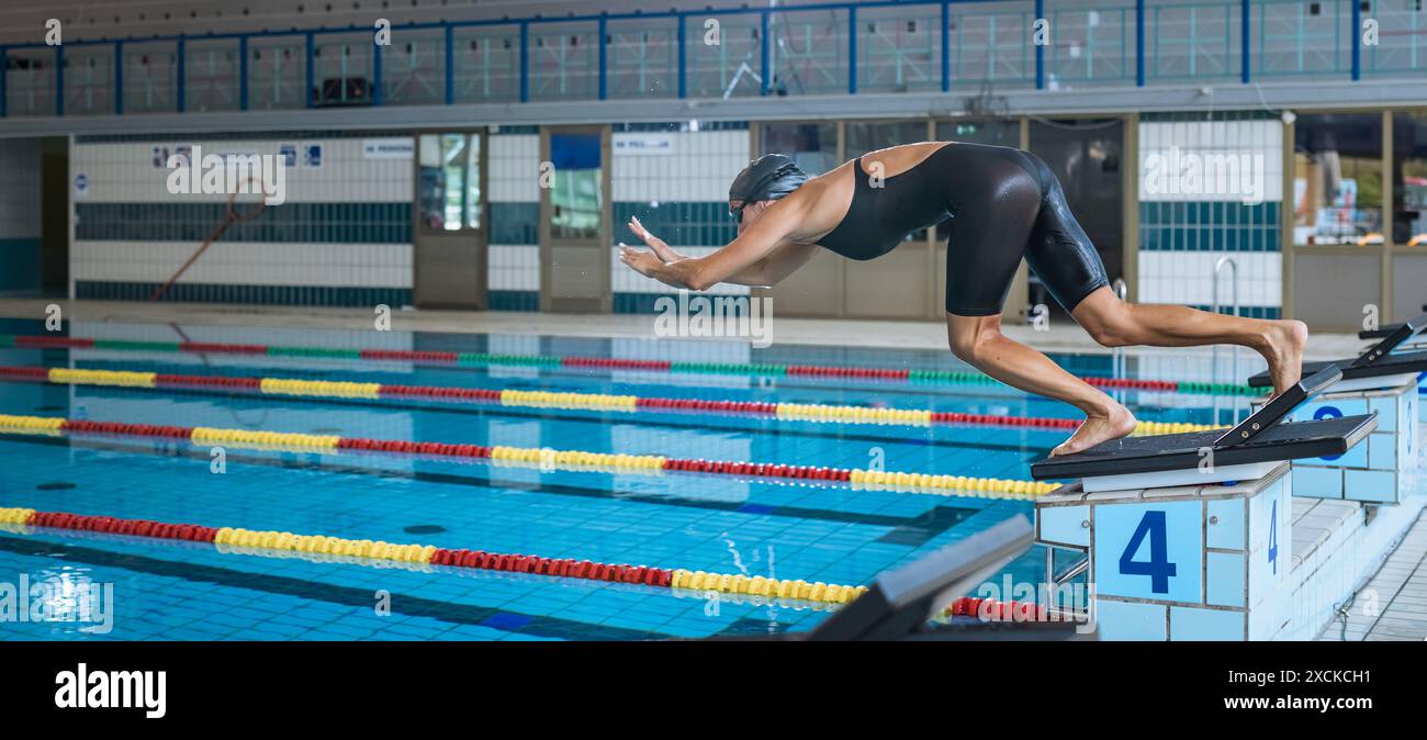 Professional female swimmer preparing and jumping off the starting ...