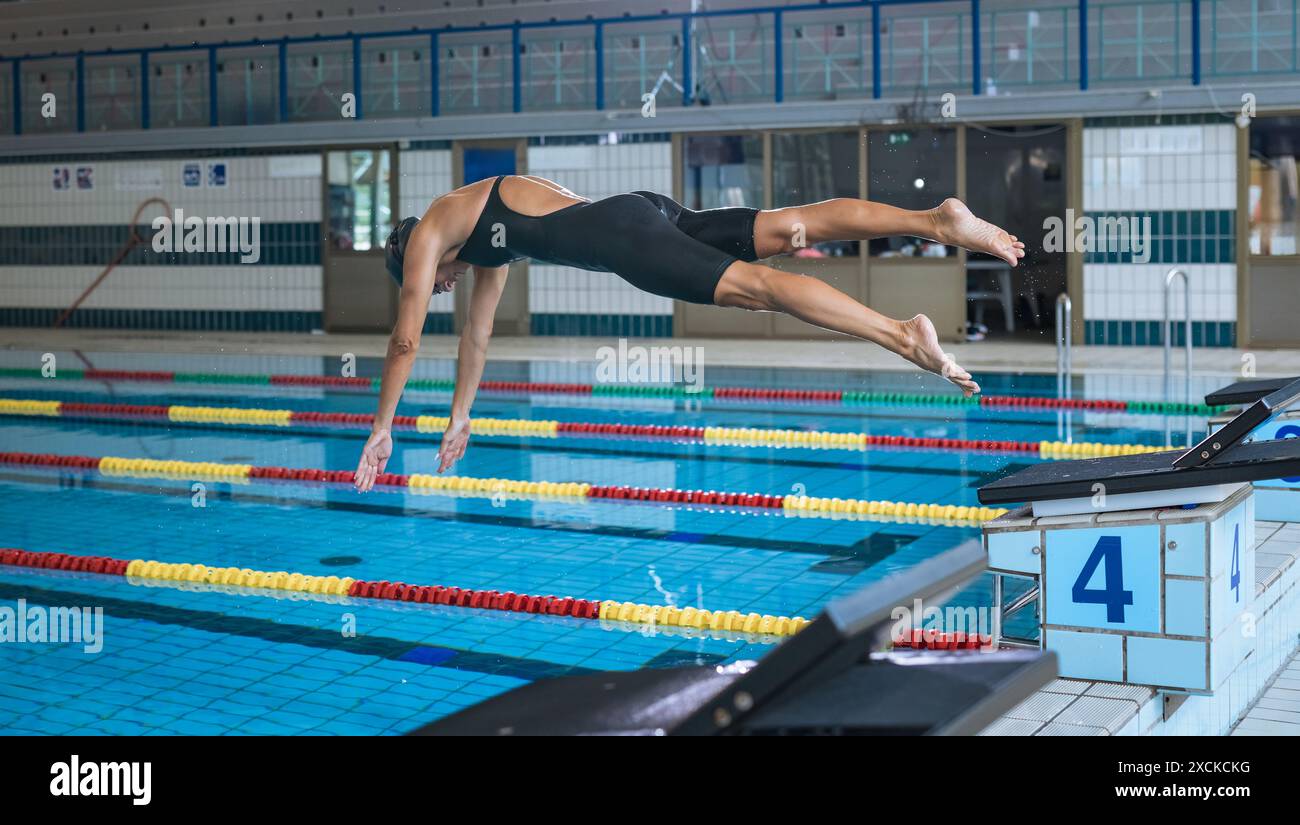 Professional female swimmer preparing and jumping off the starting ...