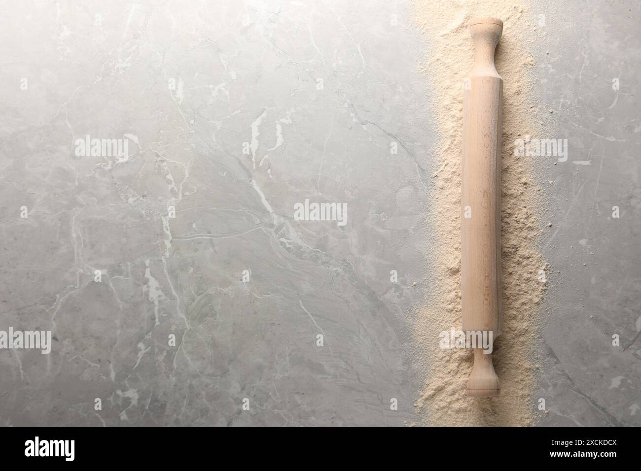 Flour and rolling pin on grey marble table, top view. Space for text ...