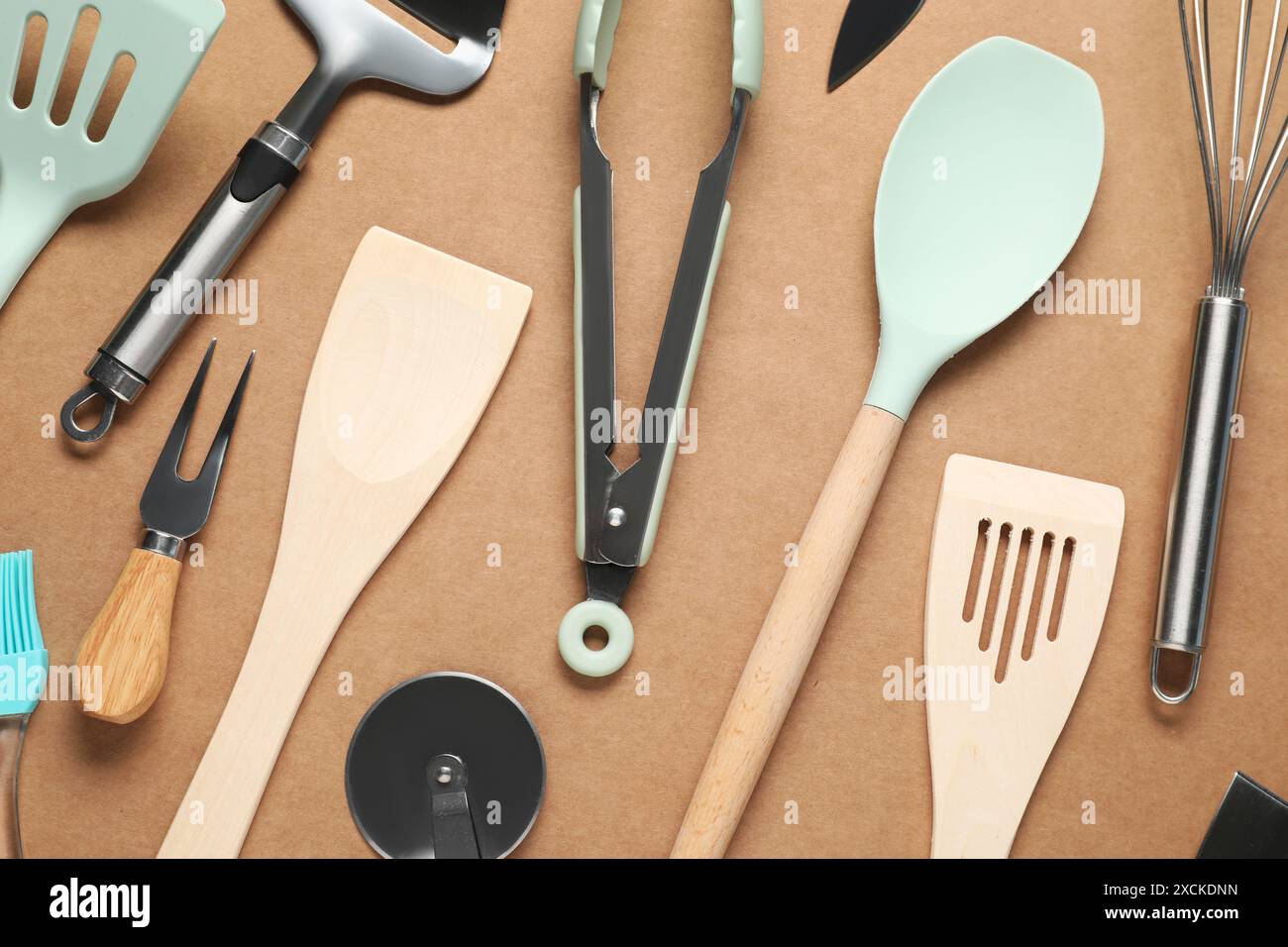 Different spatulas and other kitchen utensils on brown background, flat ...