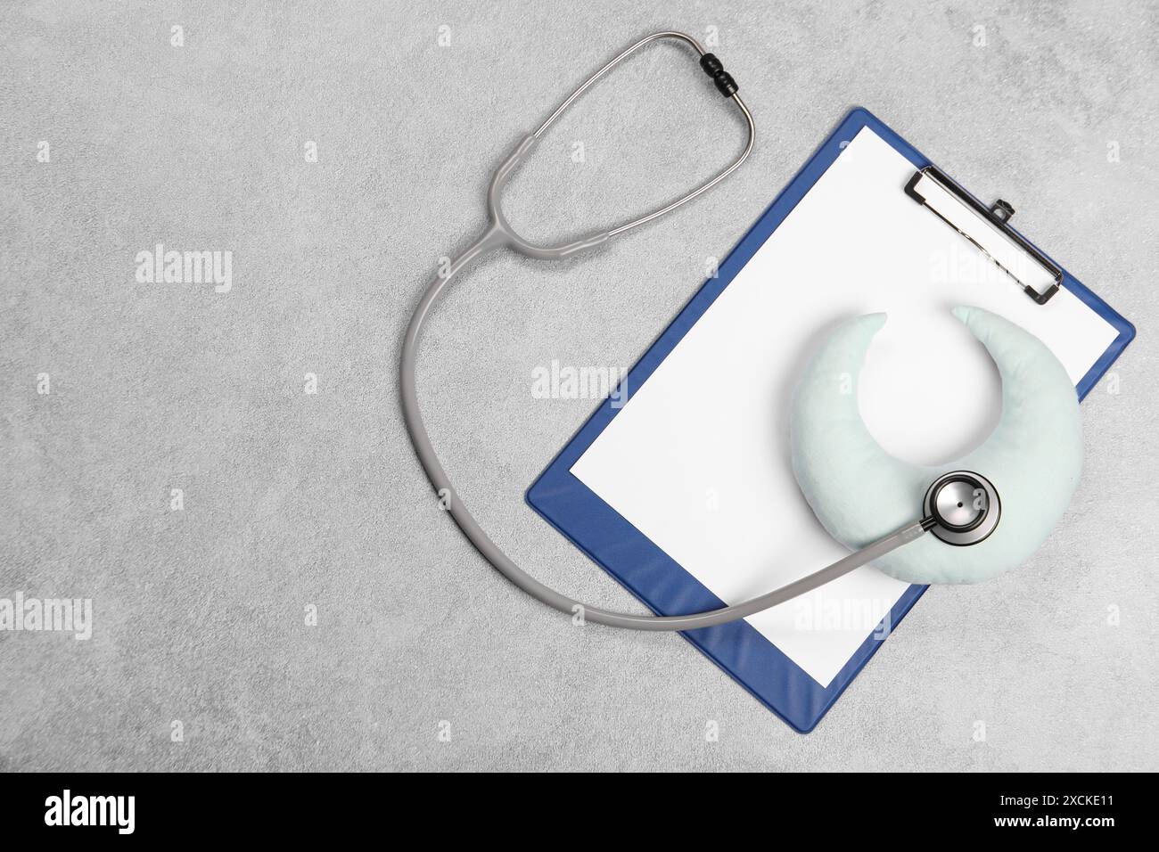 Clipboard, stethoscope and pillow on gray textured background, top view ...