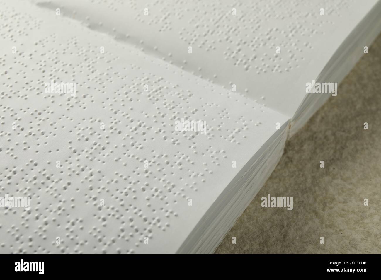 Book with Braille text on beige textured table, closeup. Education and ...