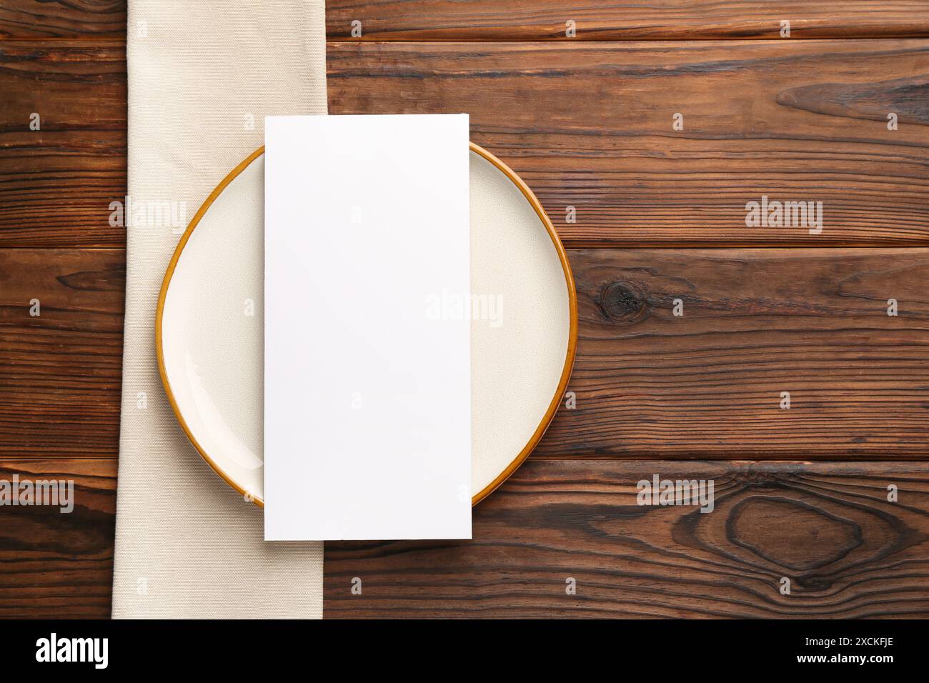 Empty menu, plate and napkin on wooden table, top view. Mockup for ...