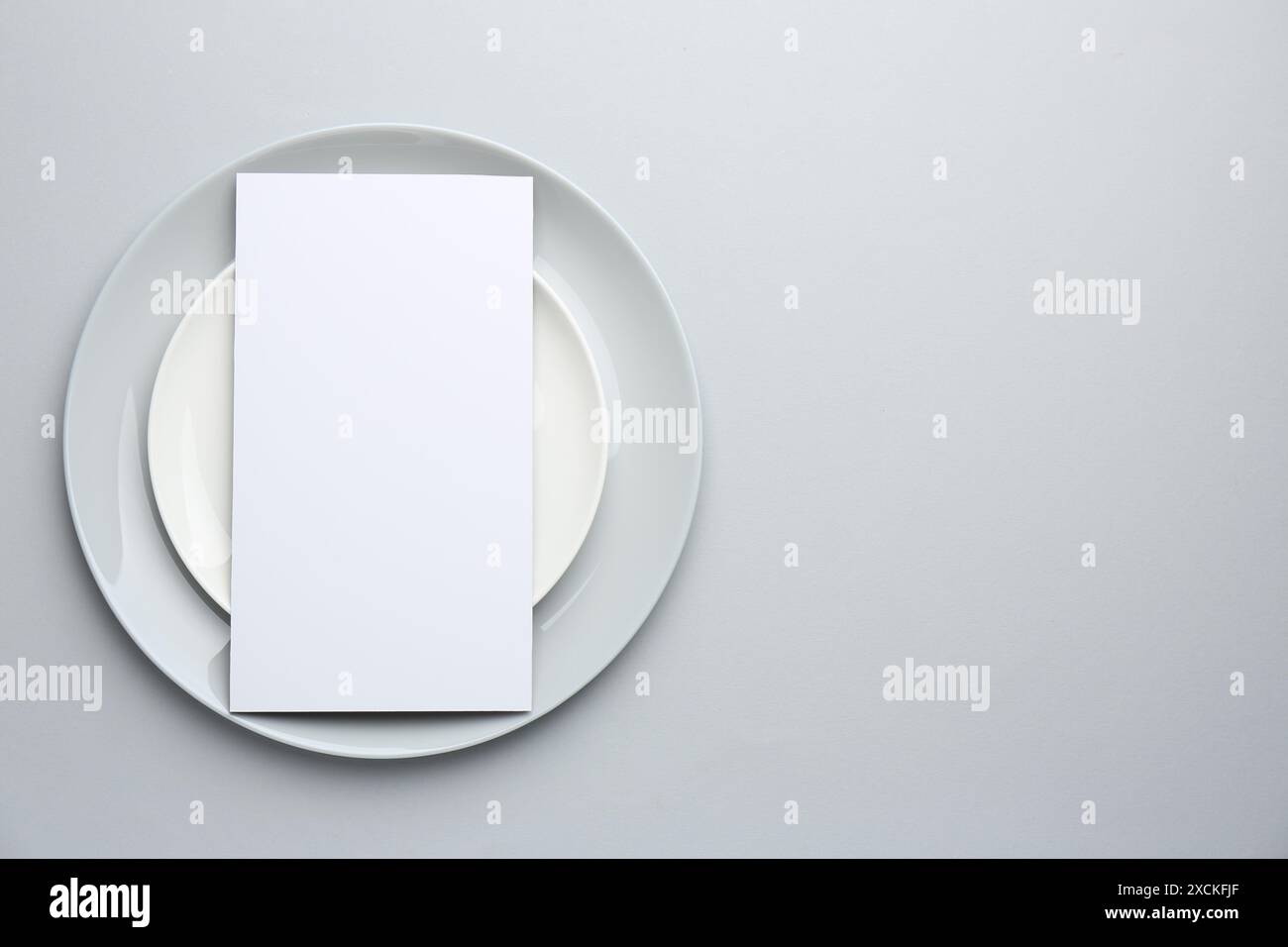 Empty menu and plates on light grey background, top view. Mockup for ...