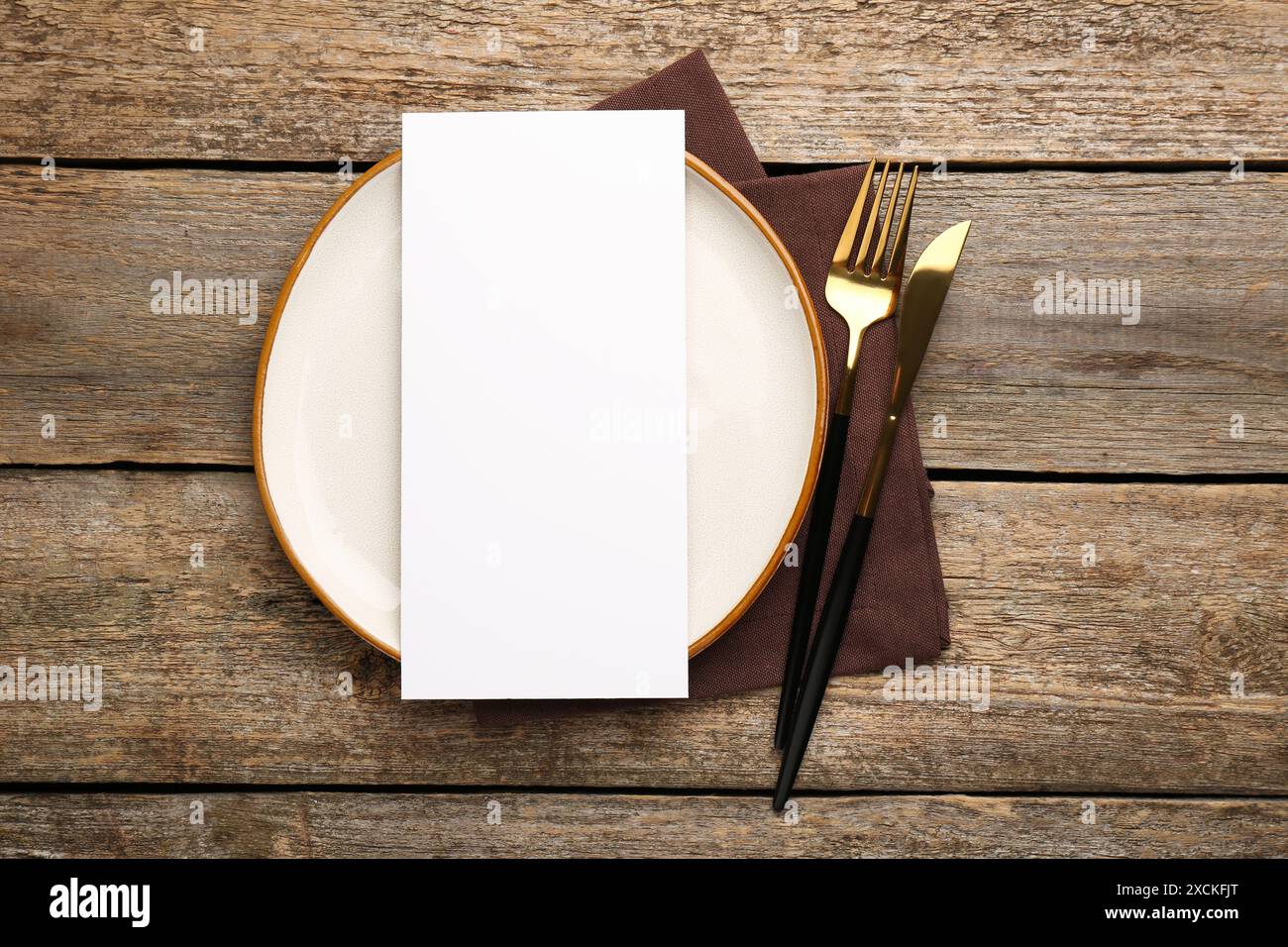 Empty menu, cutlery, plate and napkin on wooden table, top view. Mockup ...