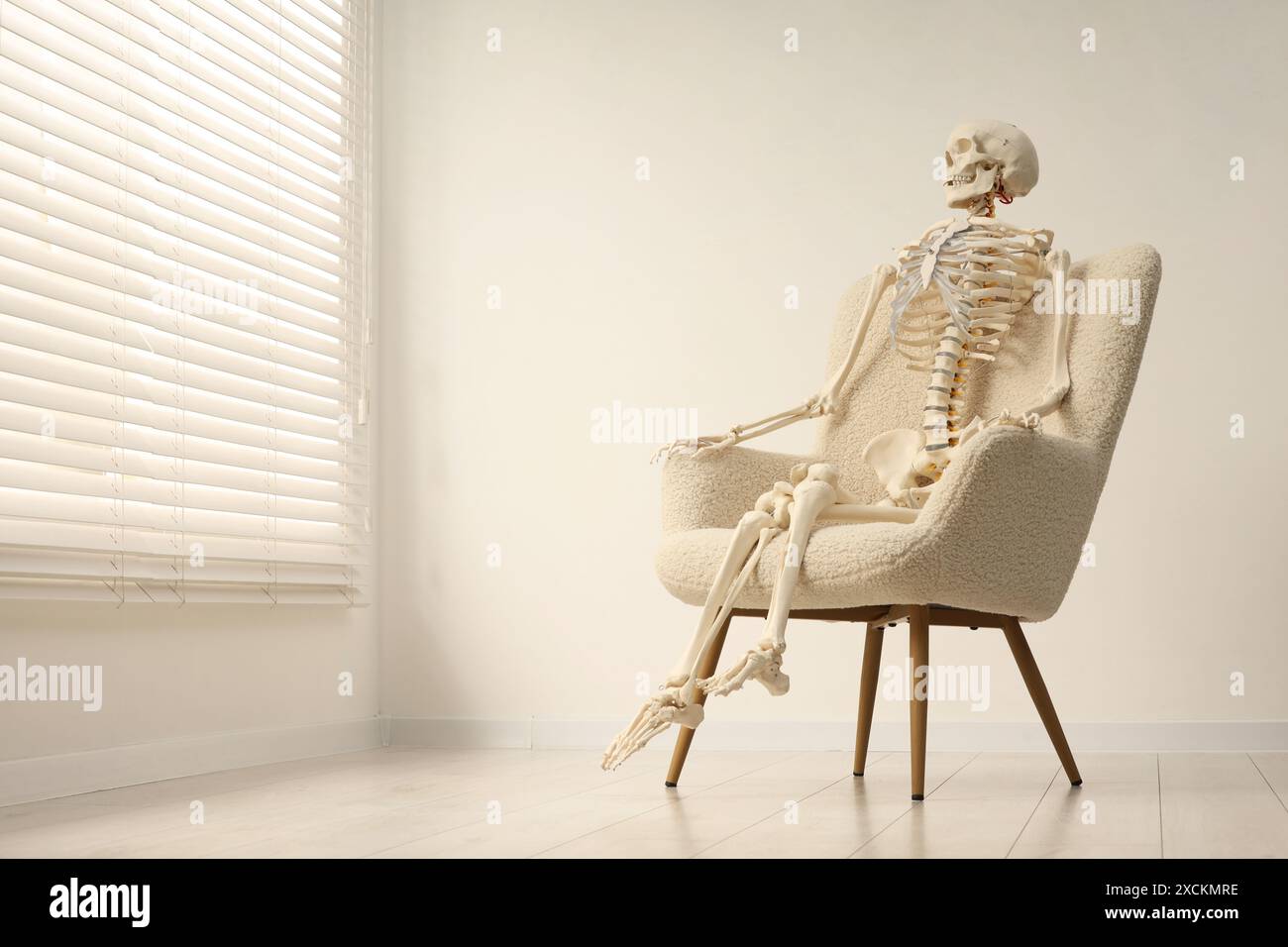 Waiting concept. Human skeleton sitting in armchair indoors, space for ...