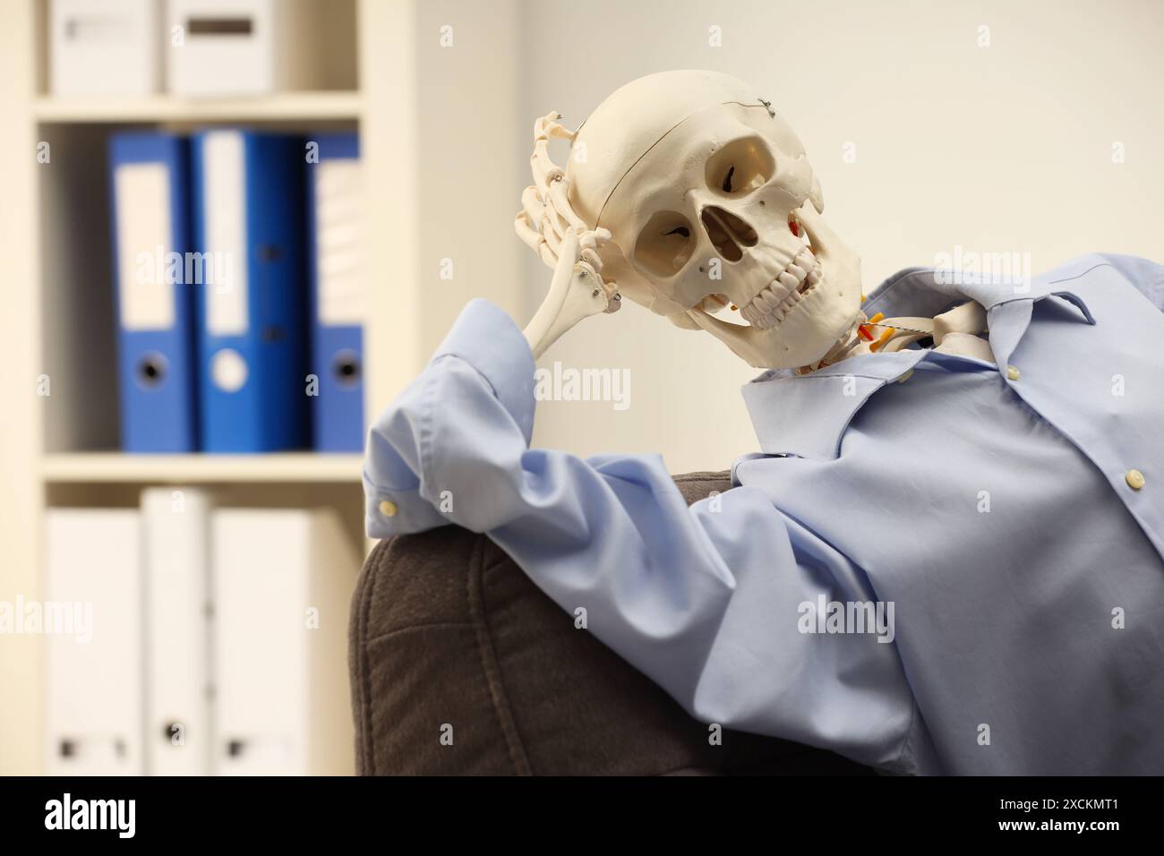 Waiting concept. Human skeleton sitting in armchair at office Stock ...