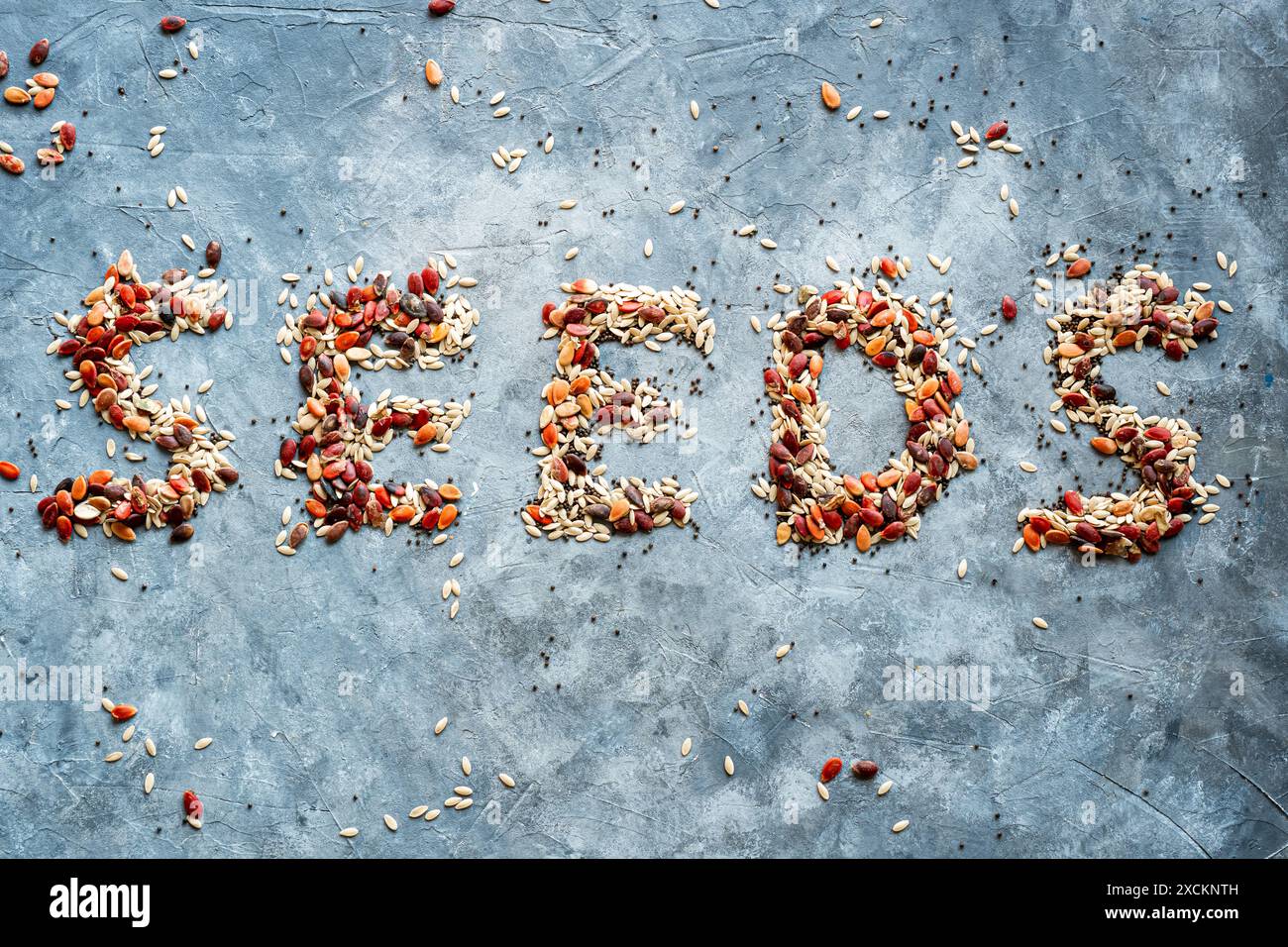 english word SEEDS is laid out on a grey background of dried seeds ...