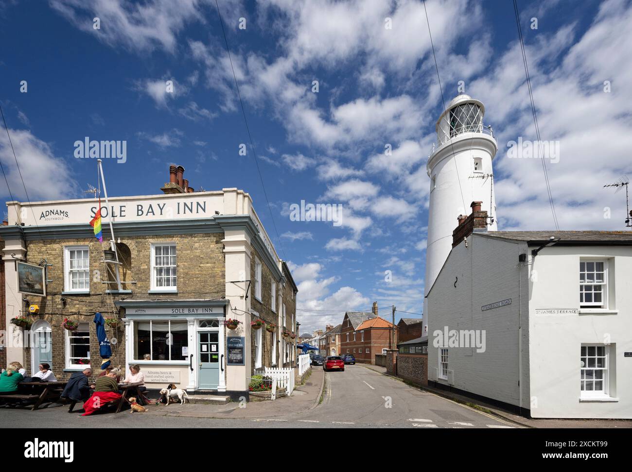 Sole bay Inn pub alongside Iconic white lighthouse inland behind row of ...