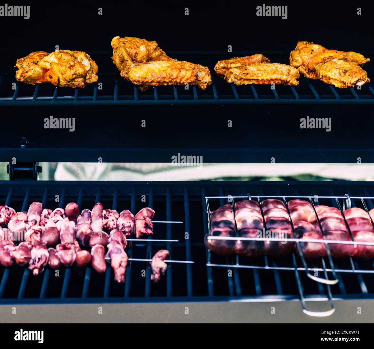 A close-up image of a charcoal grill with a variety of meats grilling ...