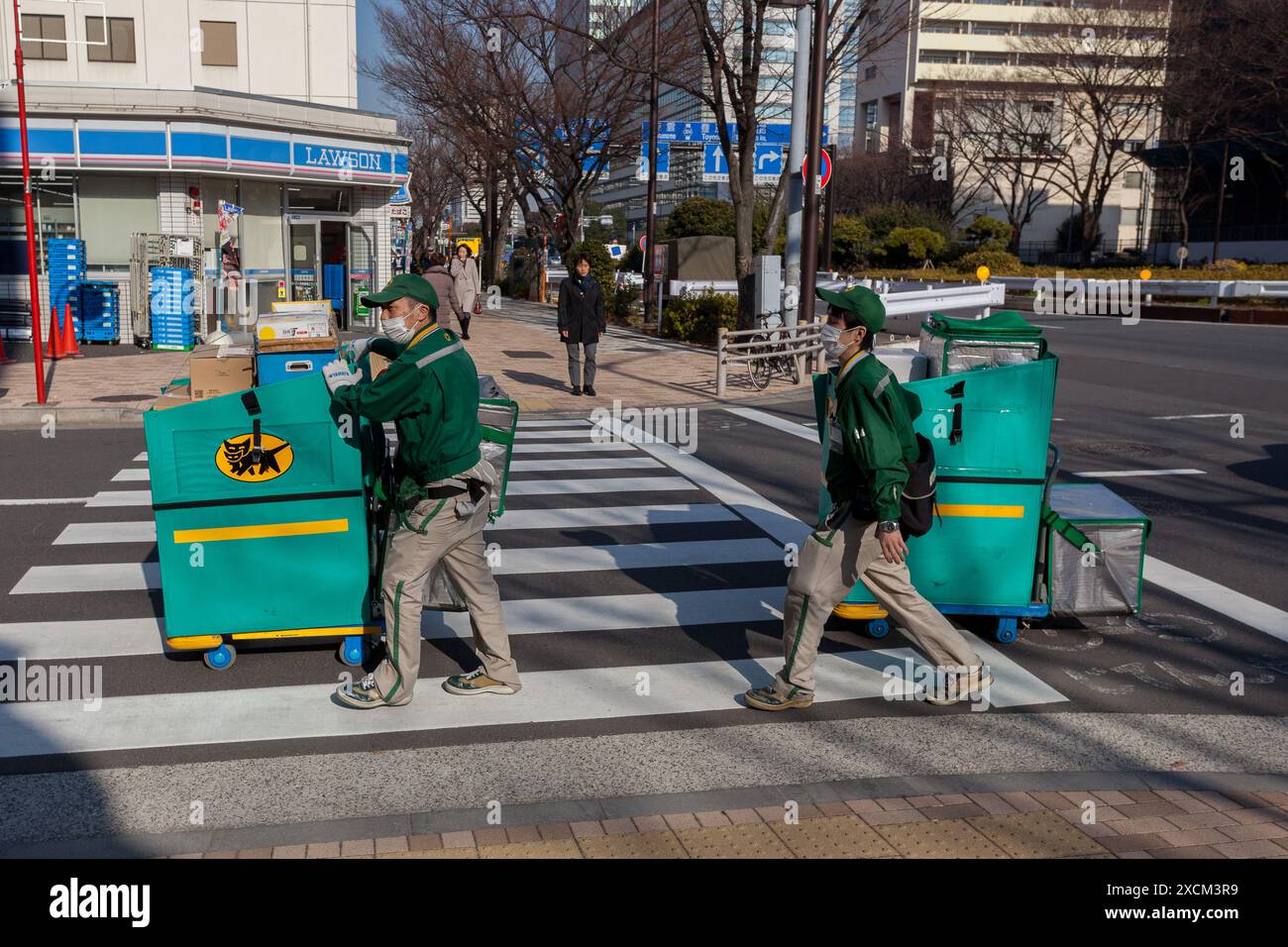 Two Yamato delivery company delivery men wheel trolleys in the street ...