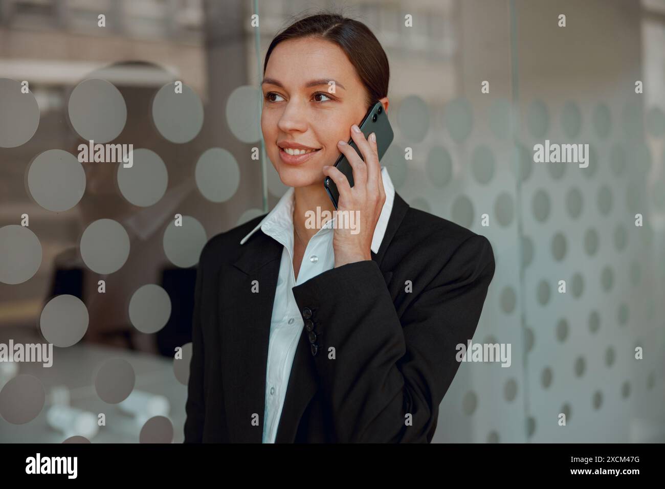 Businesswoman in formal attire talking on the phone at a modern office ...