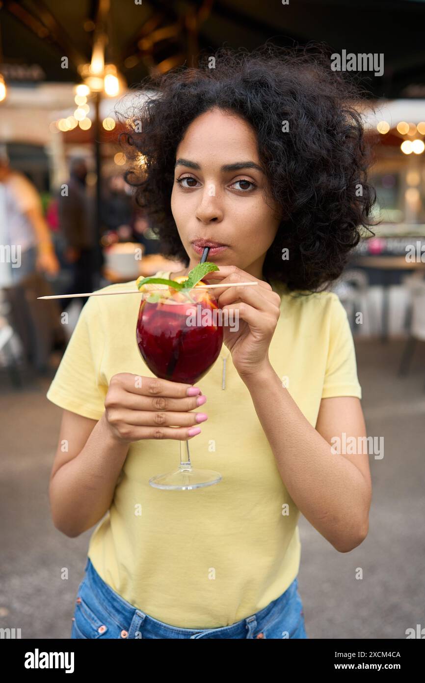 Young woman sipping a drink through a straw at an outdoor terrace Stock ...