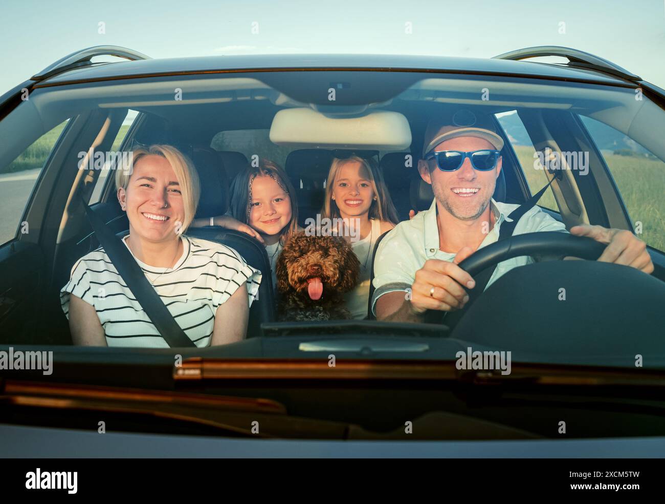 Happy family enjoys road trip together, with fluffy brown Maltipoo dog ...