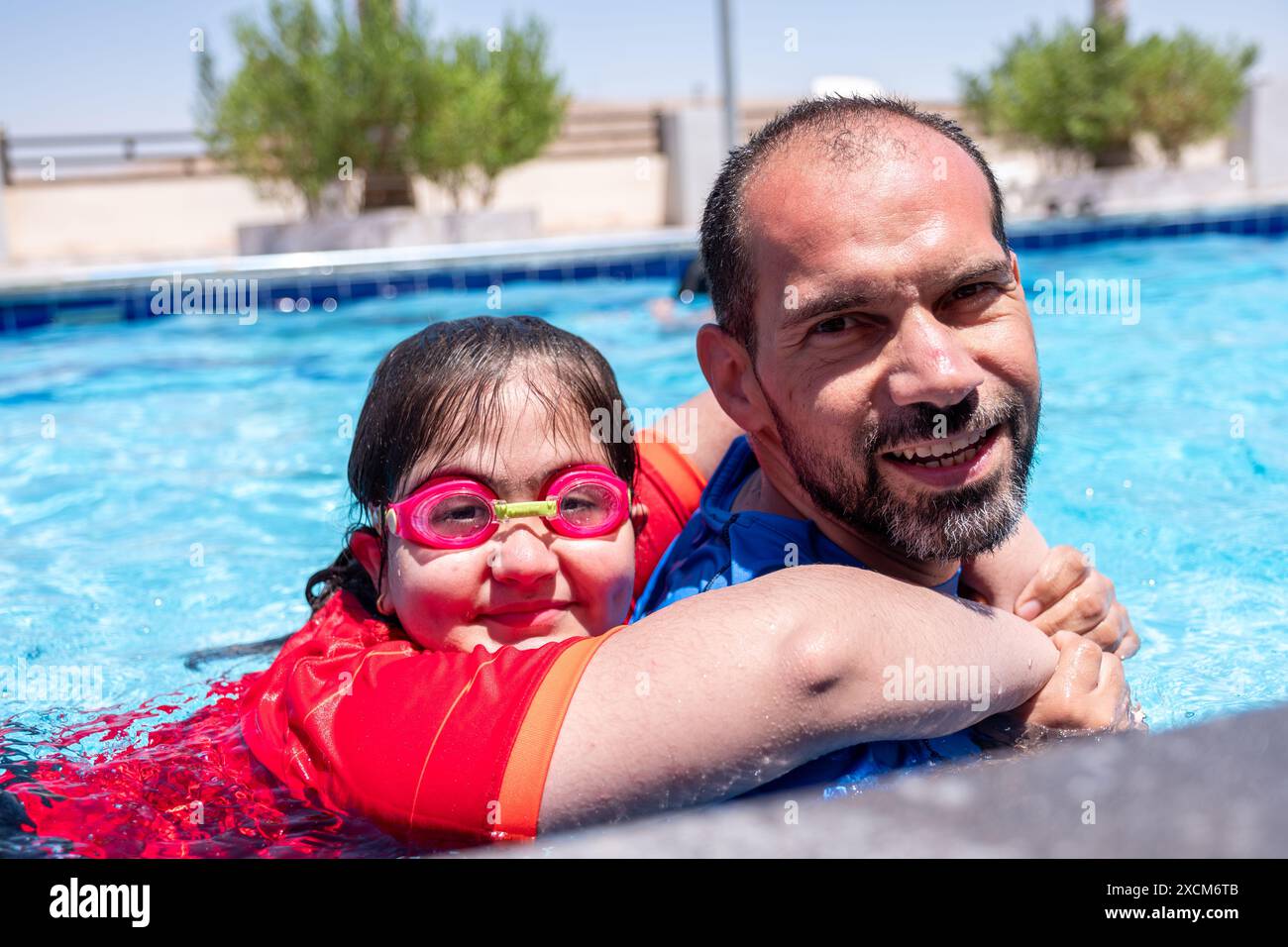 Mid age male having fun with daughter in the pool during summer ...
