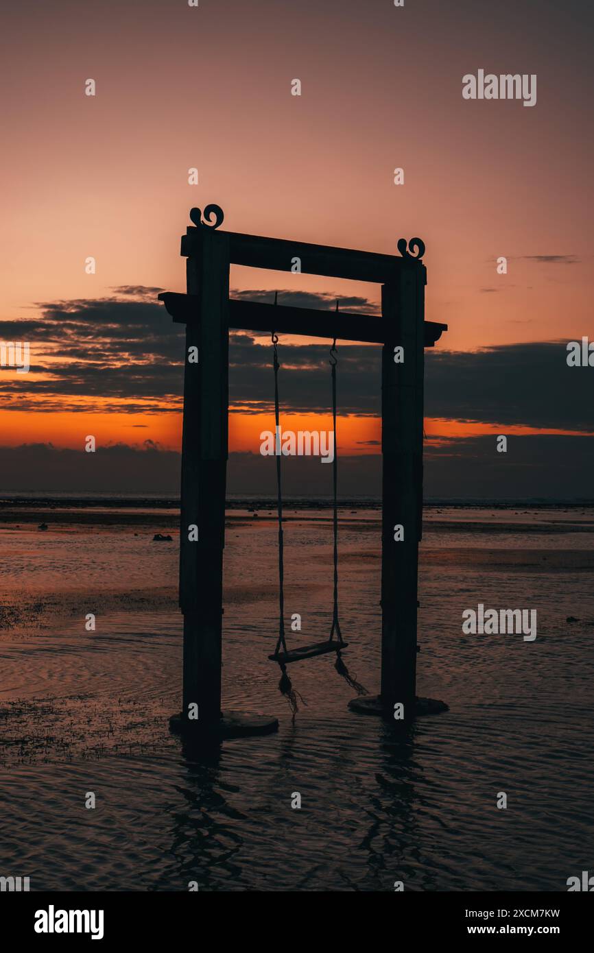 Silhouette of a swing set at sunset on the beach. The vibrant sky ...