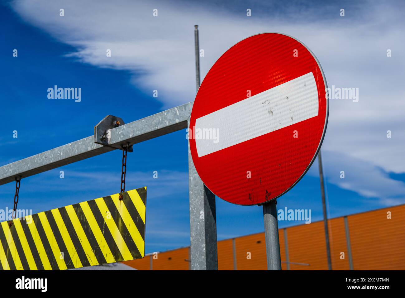 A Red No Entry Sign and Yellow Striped Barrier Against a Blue Sky Stock ...