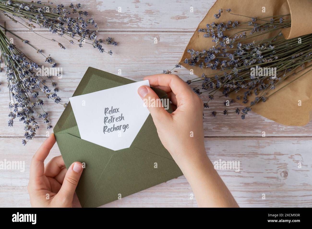 Female hands taking paper card note with text RELAX REFRESH RECHARGE ...