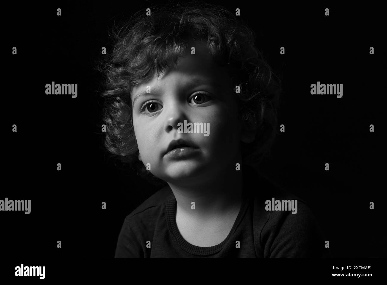 Portrait of cute little boy on dark background. Black and white effect ...