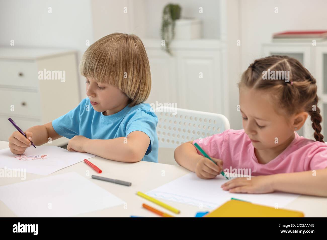 Cute little children drawing at table indoors Stock Photo - Alamy