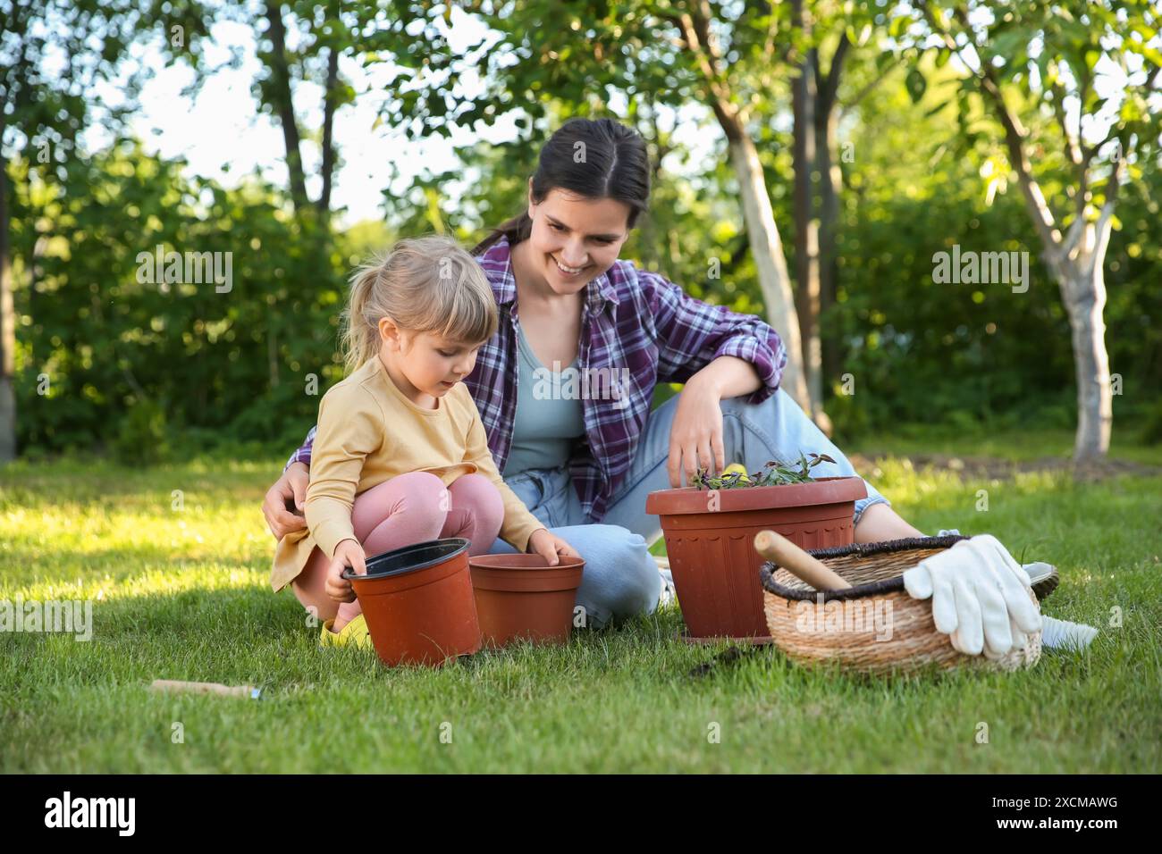 Mother and her daughter planting tree together in garden Stock Photo ...