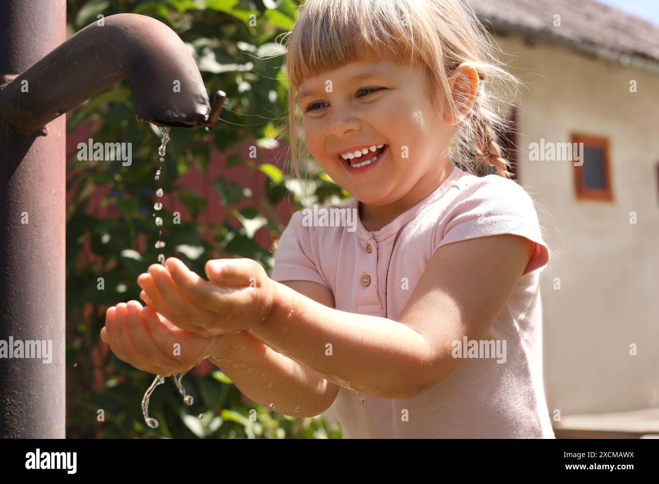 Water scarcity. Cute little girl drawing water with hands from tap ...